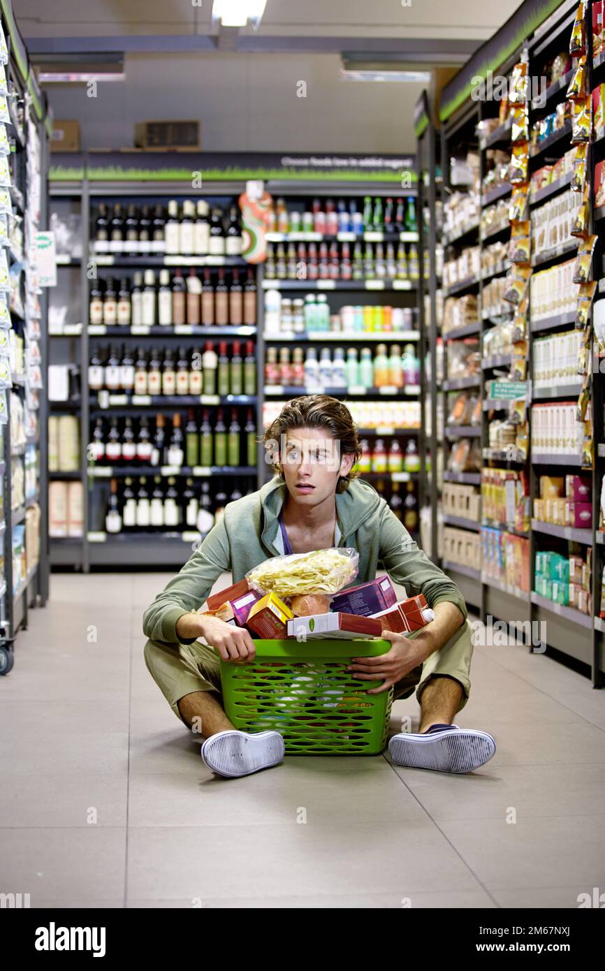 Variety overload. A young man sitting on the floor anxiously ...
