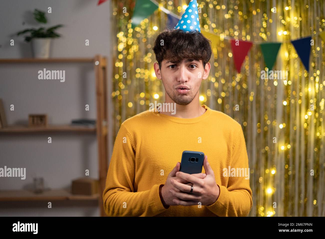 Portrait of astonished crazy guy in festive hat use cellphone read ...