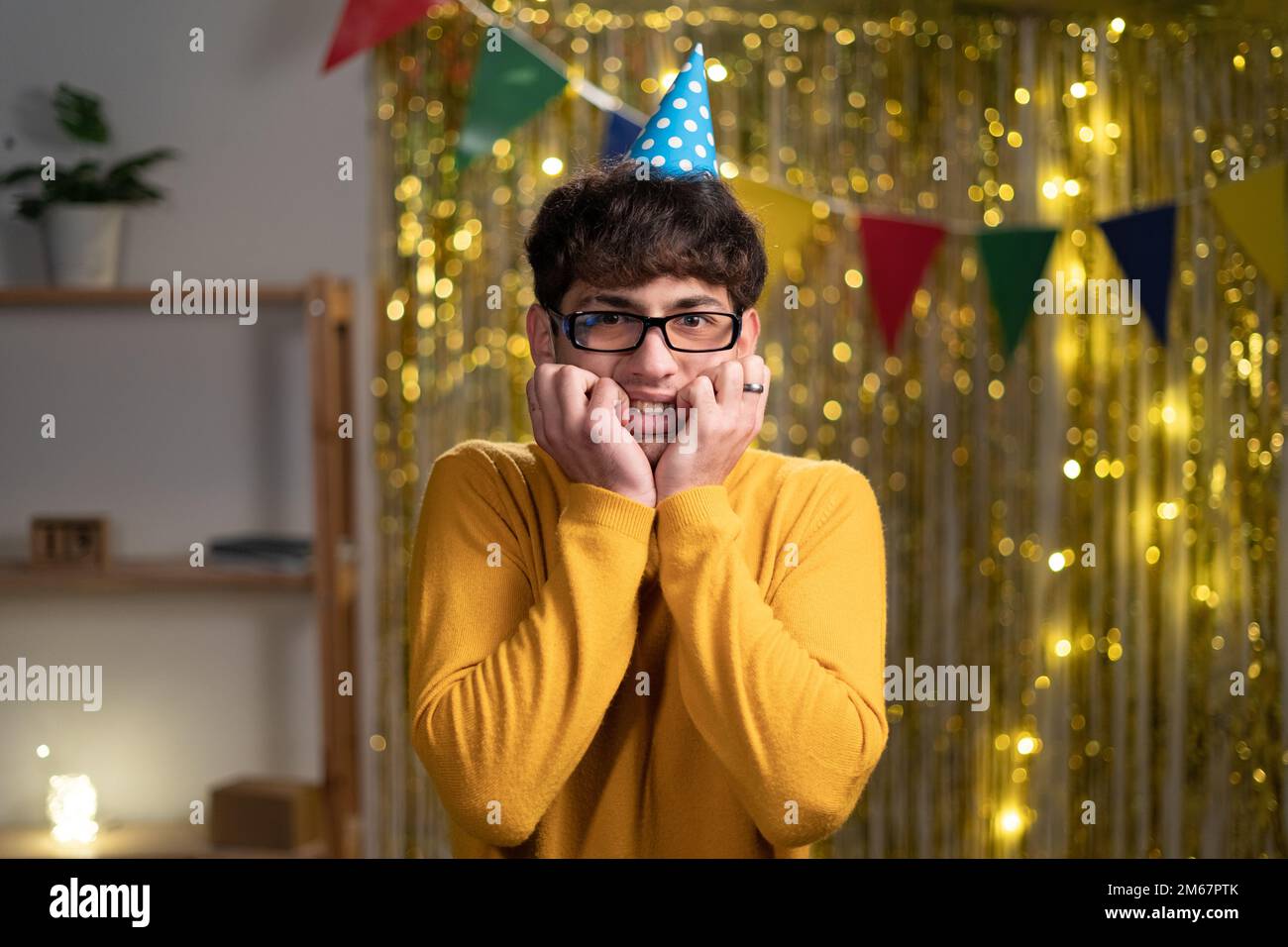 Young arab man in a party hat scared afraid, holding hands near his ...