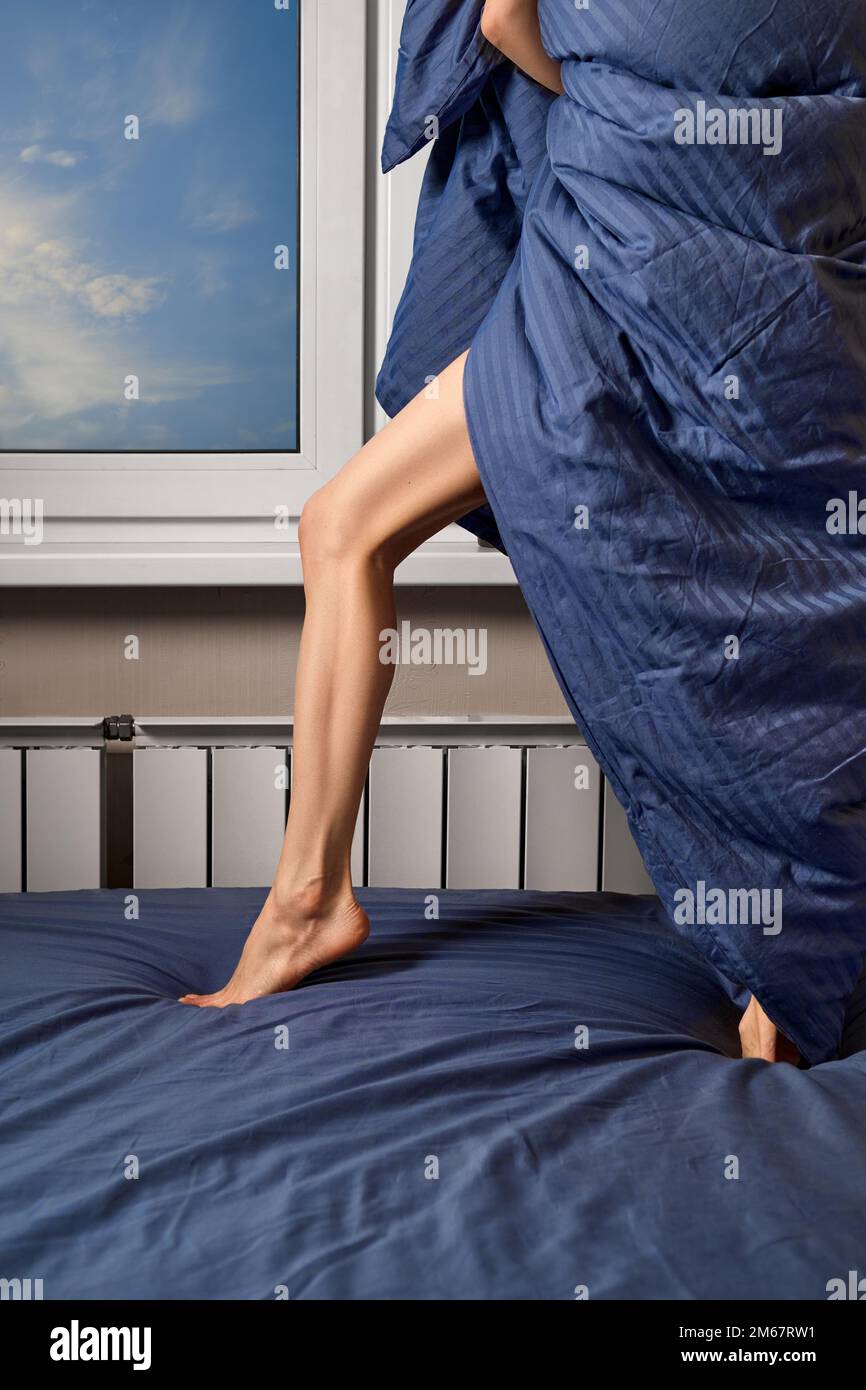 Barefoot female leg ob tiptoe sticking out of soft blanket by the ...