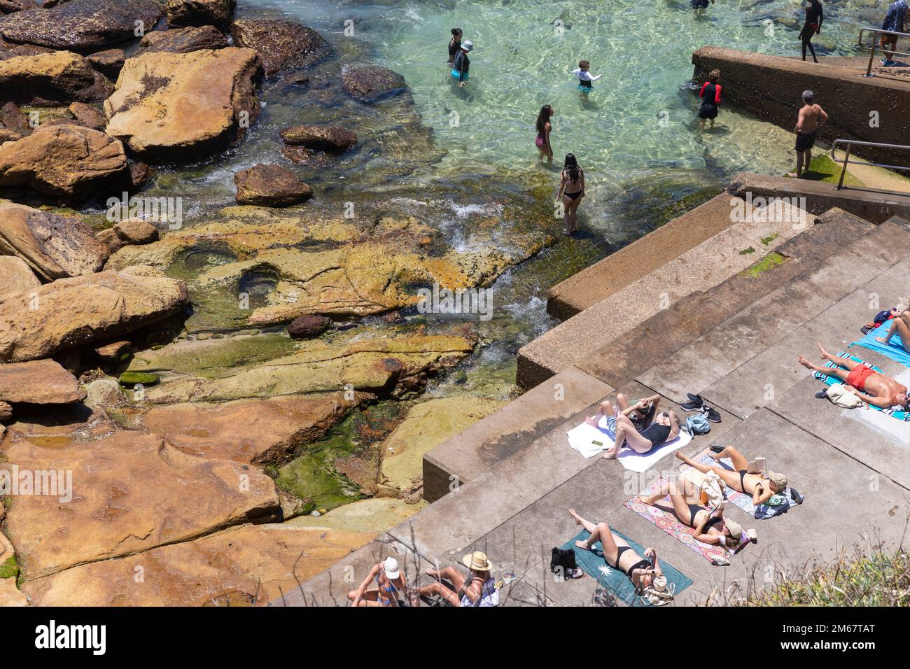 Bondi Beach people sunbathing on towels on the rocks at South Bondi ...