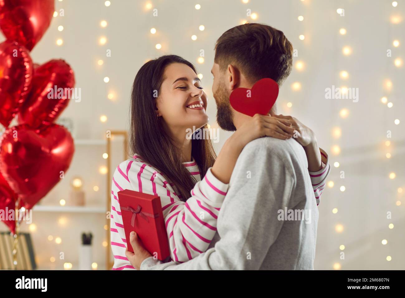 Couple in love tenderly hug each other while giving each other gifts on Valentine's Day Stock ...