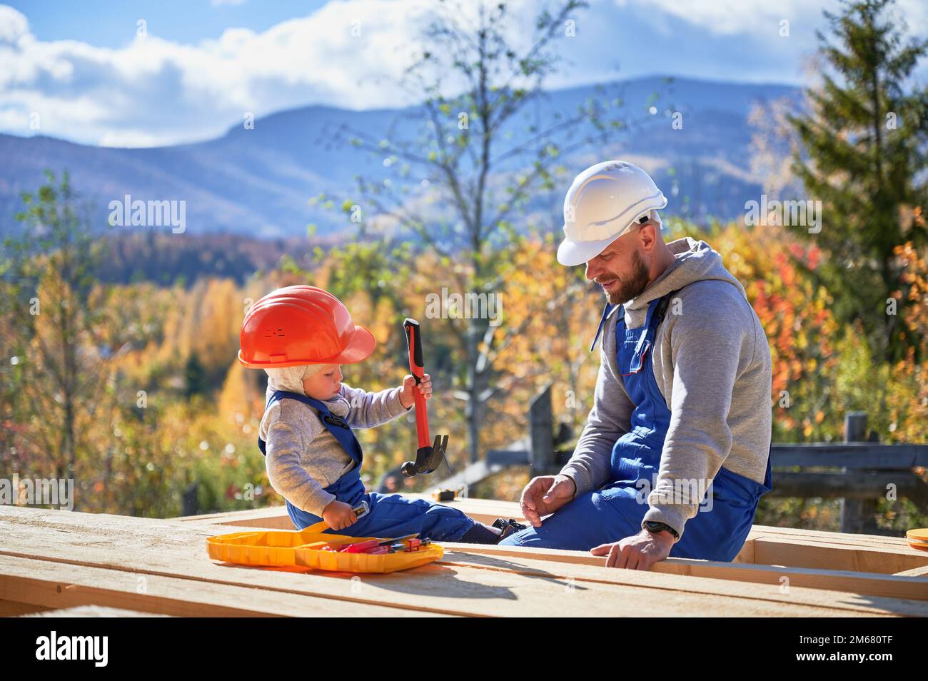 Father with toddler son building wooden frame house. Male builders ...