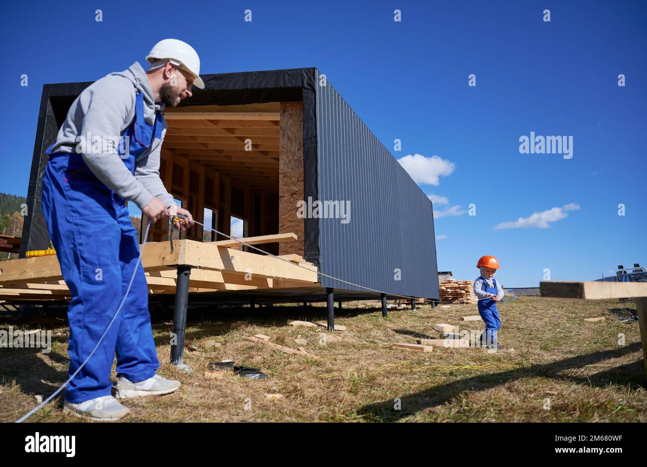 Father with toddler son building wooden frame house. Male builder and ...
