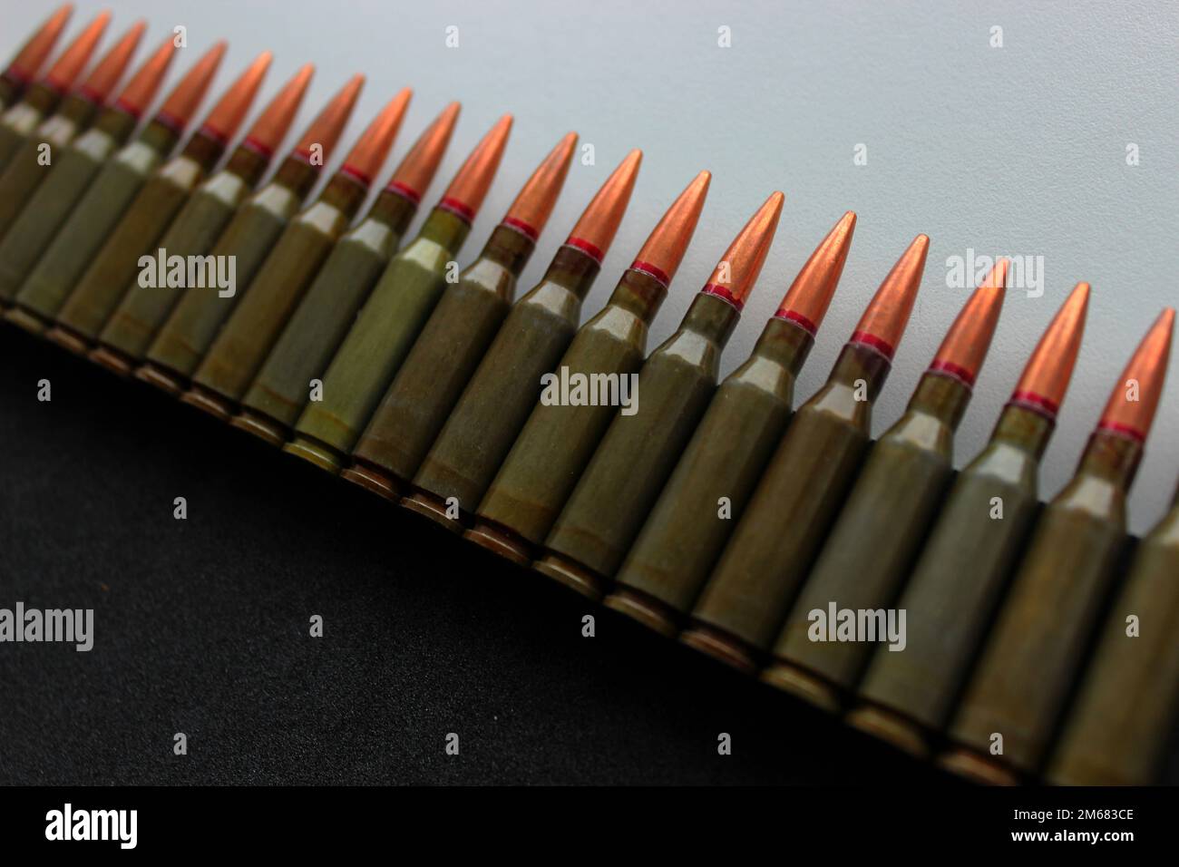 An even row of bullets lie on a background separated into a black and ...