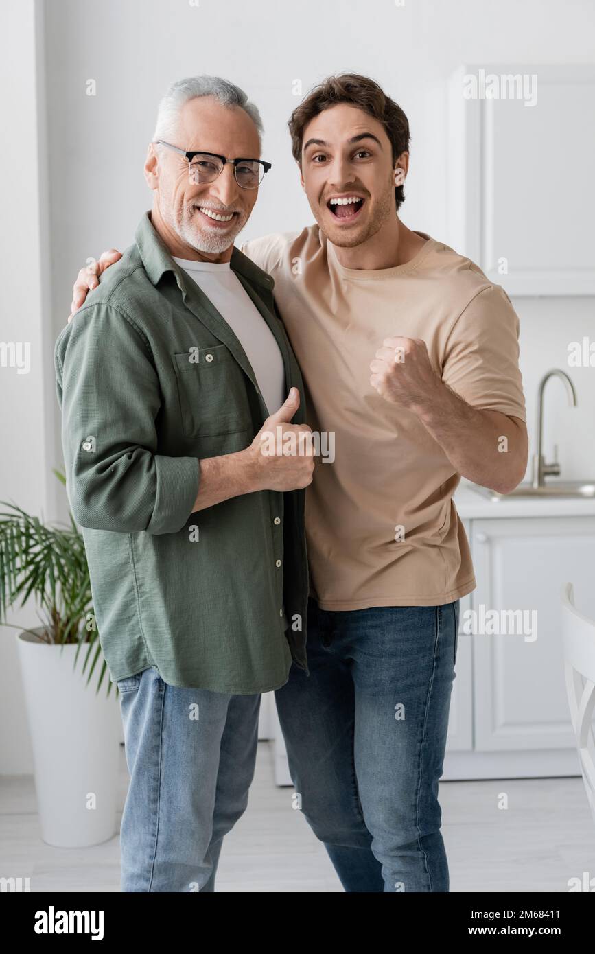 cheerful father and son showing like and success gestures while looking ...