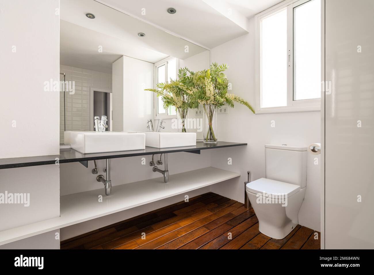 Two square sinks on black marble countertop in spacious bathroom with ...