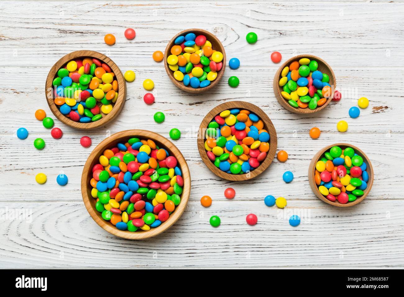 different colored round candy in bowl and jars. Top view of large ...