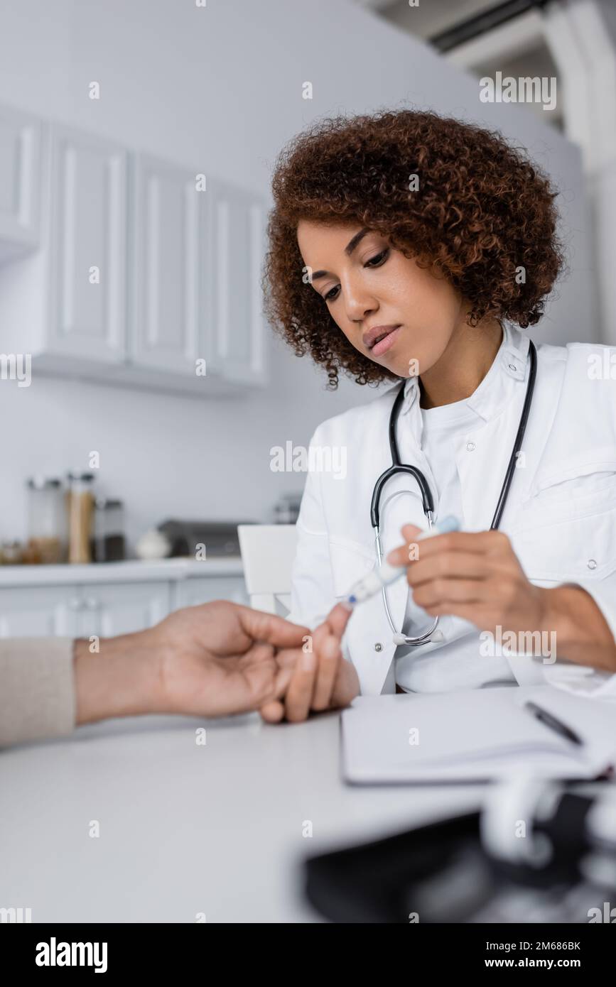curly african american doctor taking blood sample of middle aged man ...