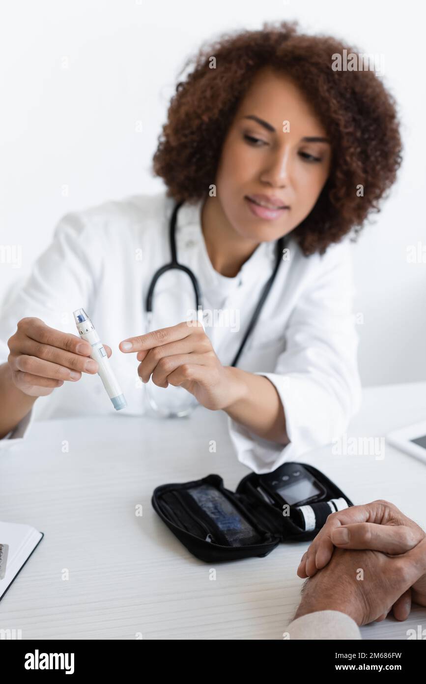 african american doctor pointing with finger at lancet pen near middle ...