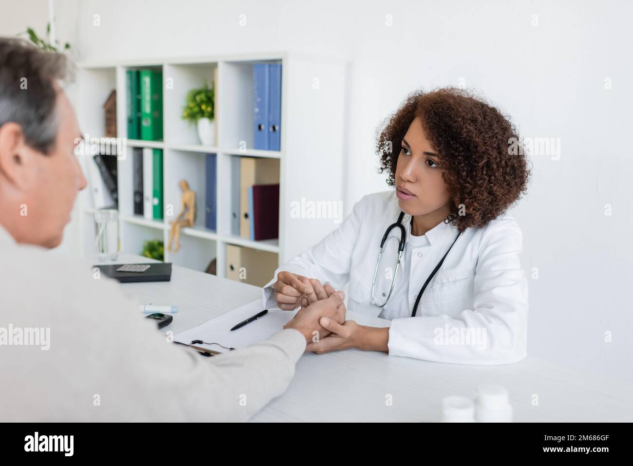 African american doctor checking hand of patient with diabetes and ...