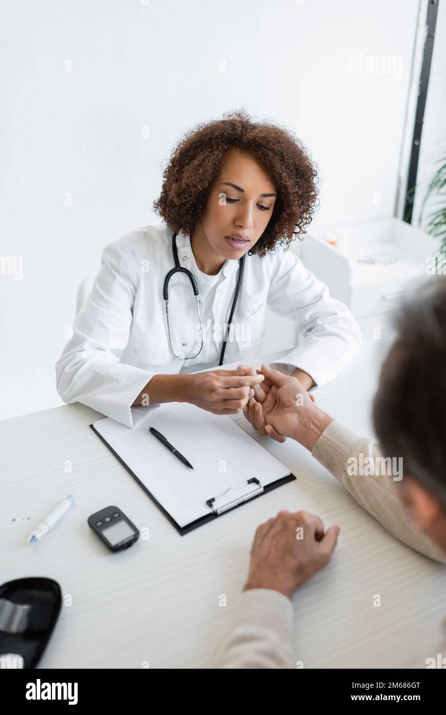 African american doctor checking hand of blurred patient with diabetes ...