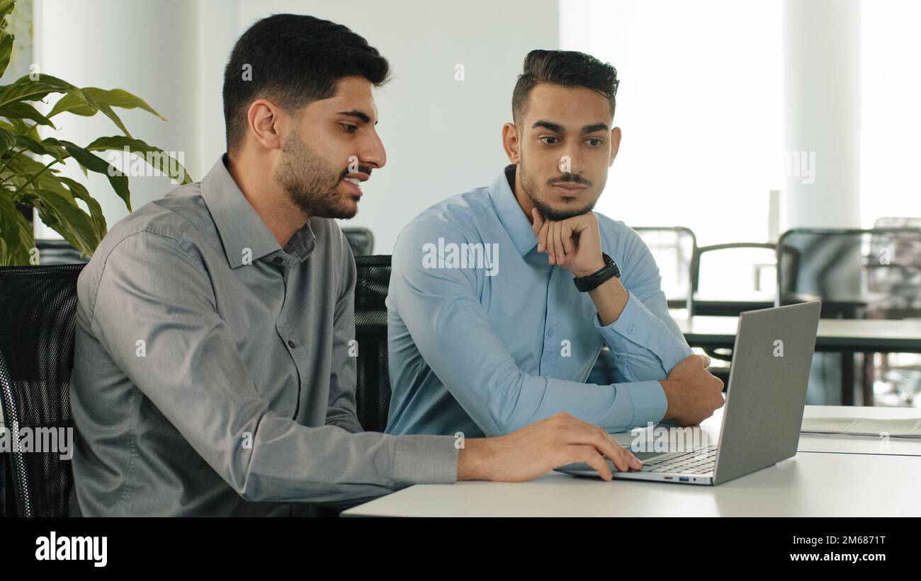 Two Indian employees sitting in modern office using laptop, young ...