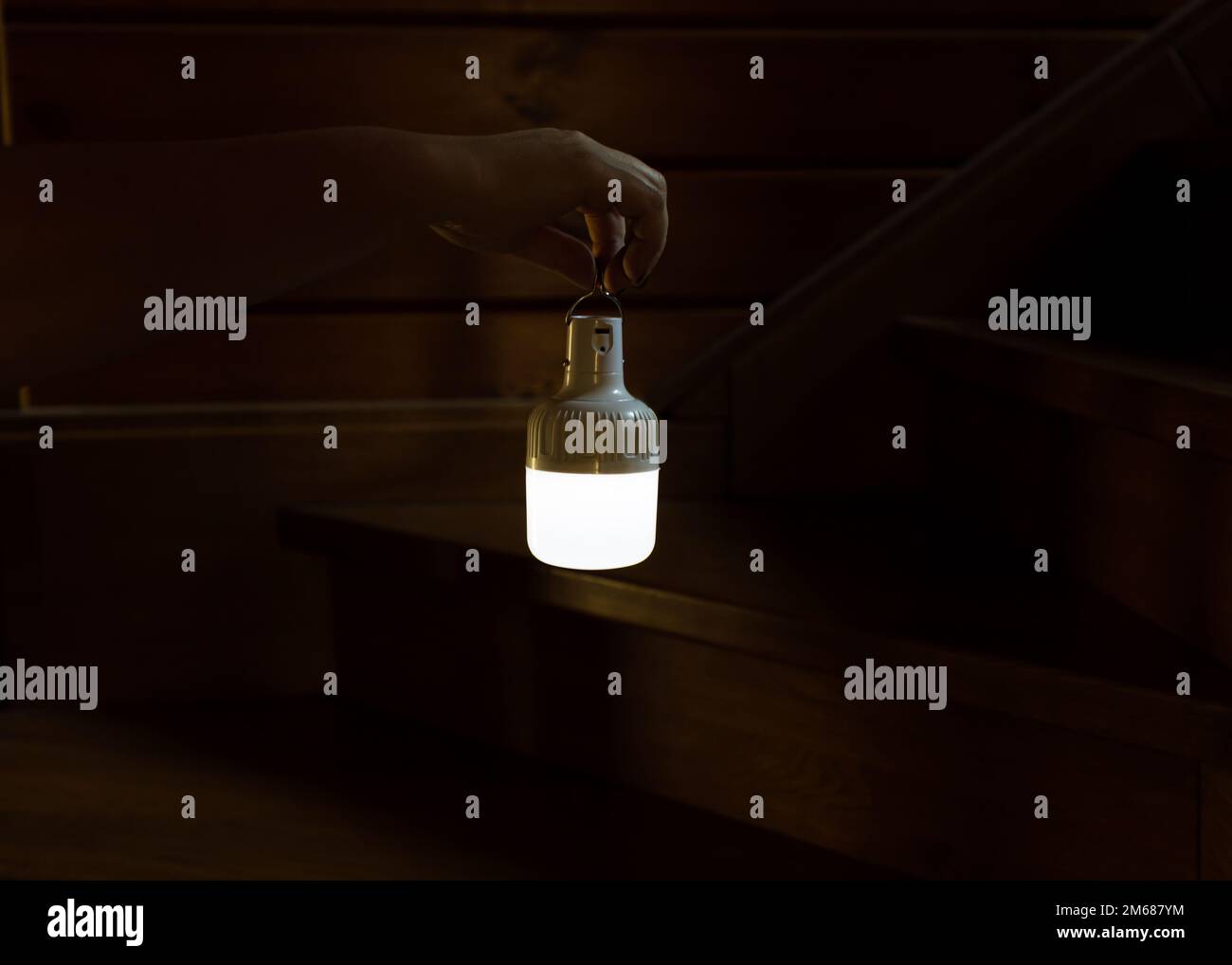 A woman's hand holds a portable rechargeable LED emergency light with a ...