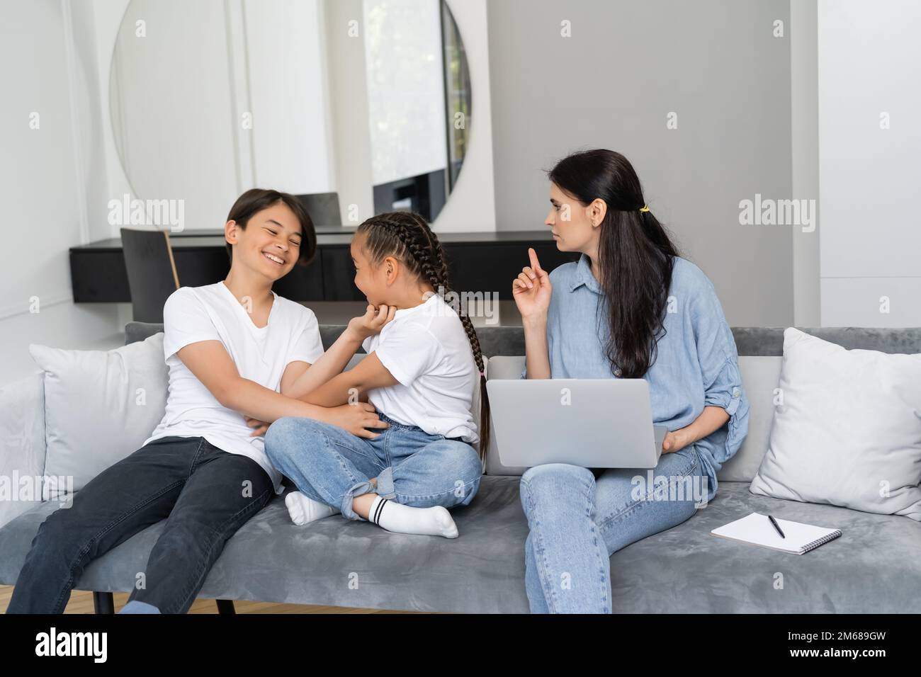 Asian kids having fun while serious mother with laptop pointing with ...