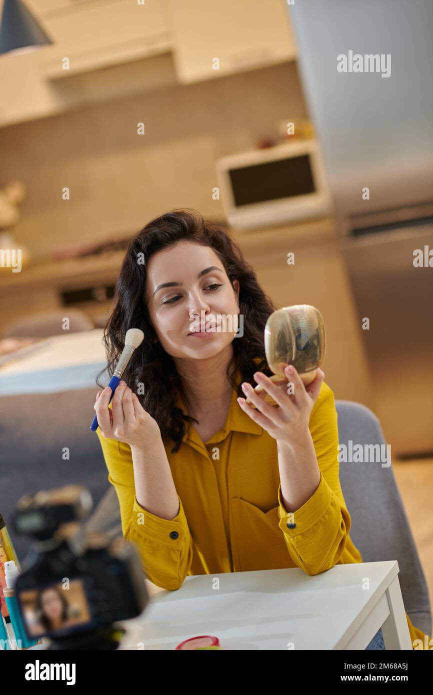 Cute dark-haired cosmetologist putting powder on her face Stock Photo ...