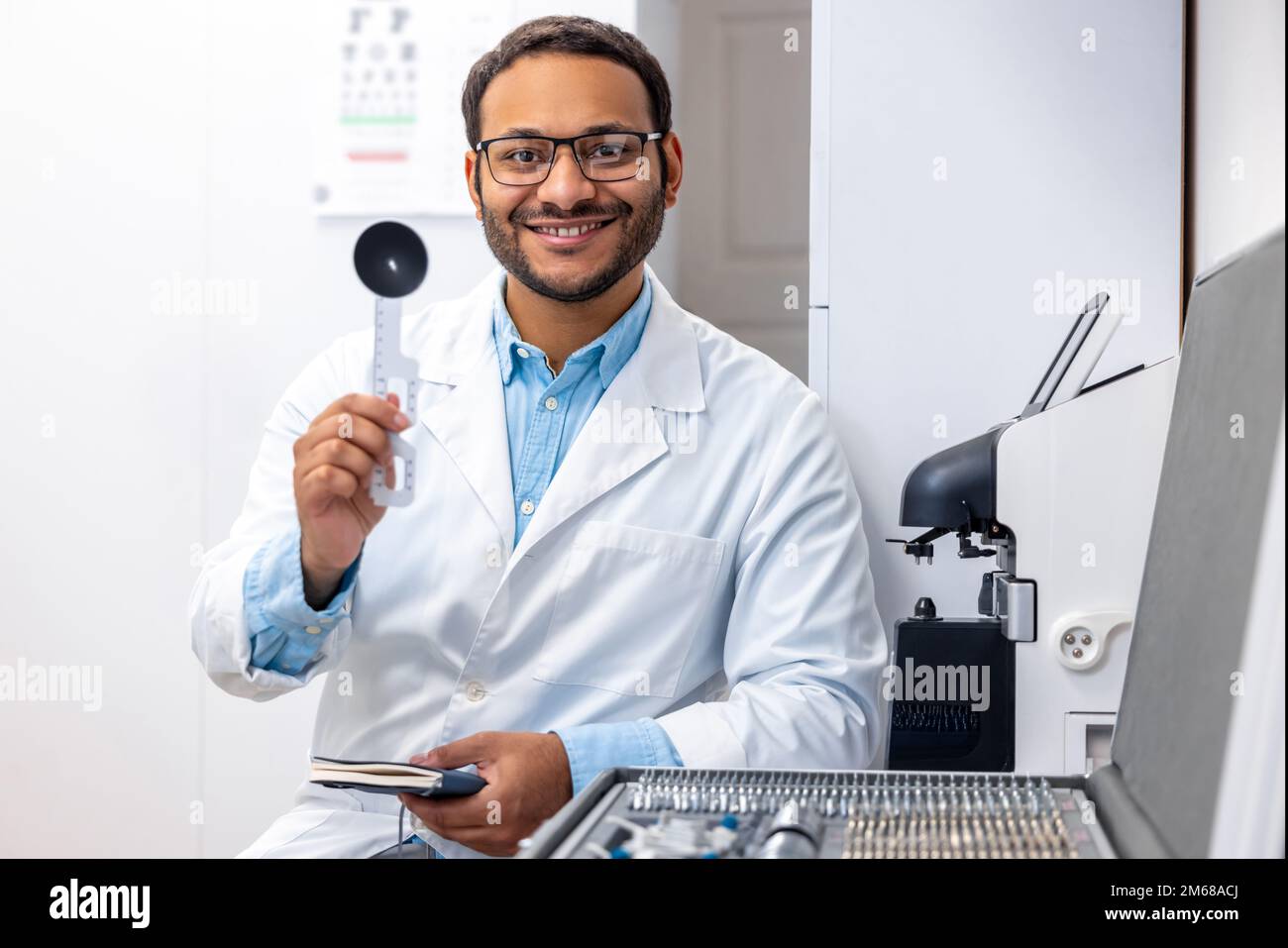 Ophtalmologyst in lab coat looking positive and smiling Stock Photo - Alamy