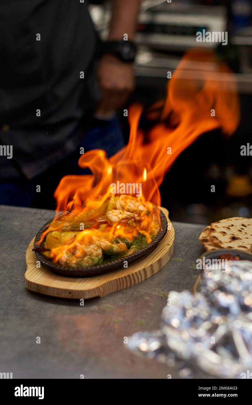 Traditional Mexican beef fajitas on fire in the kitchen, also called ...