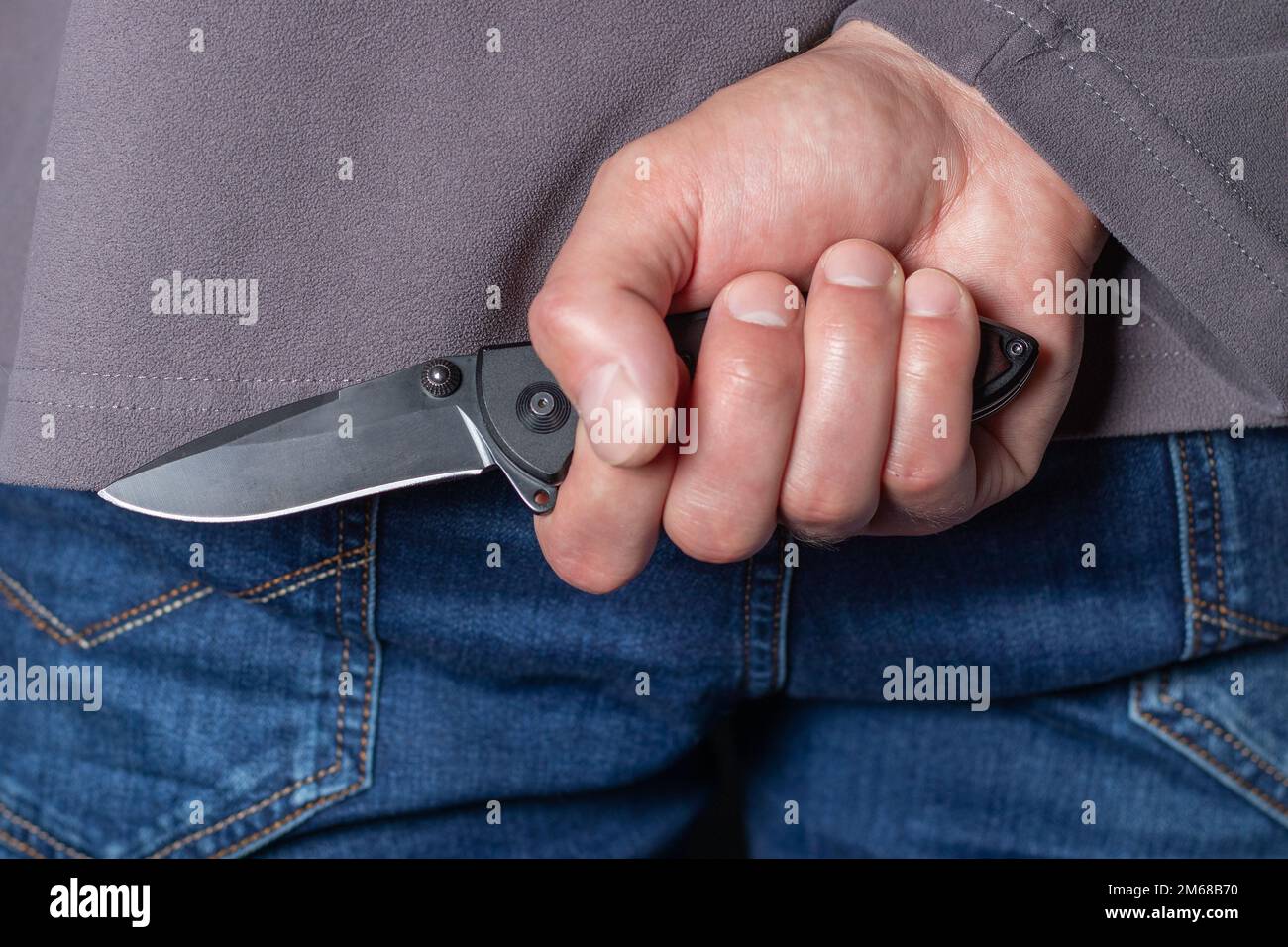 Criminal with knife weapon hidden behind his back Stock Photo - Alamy