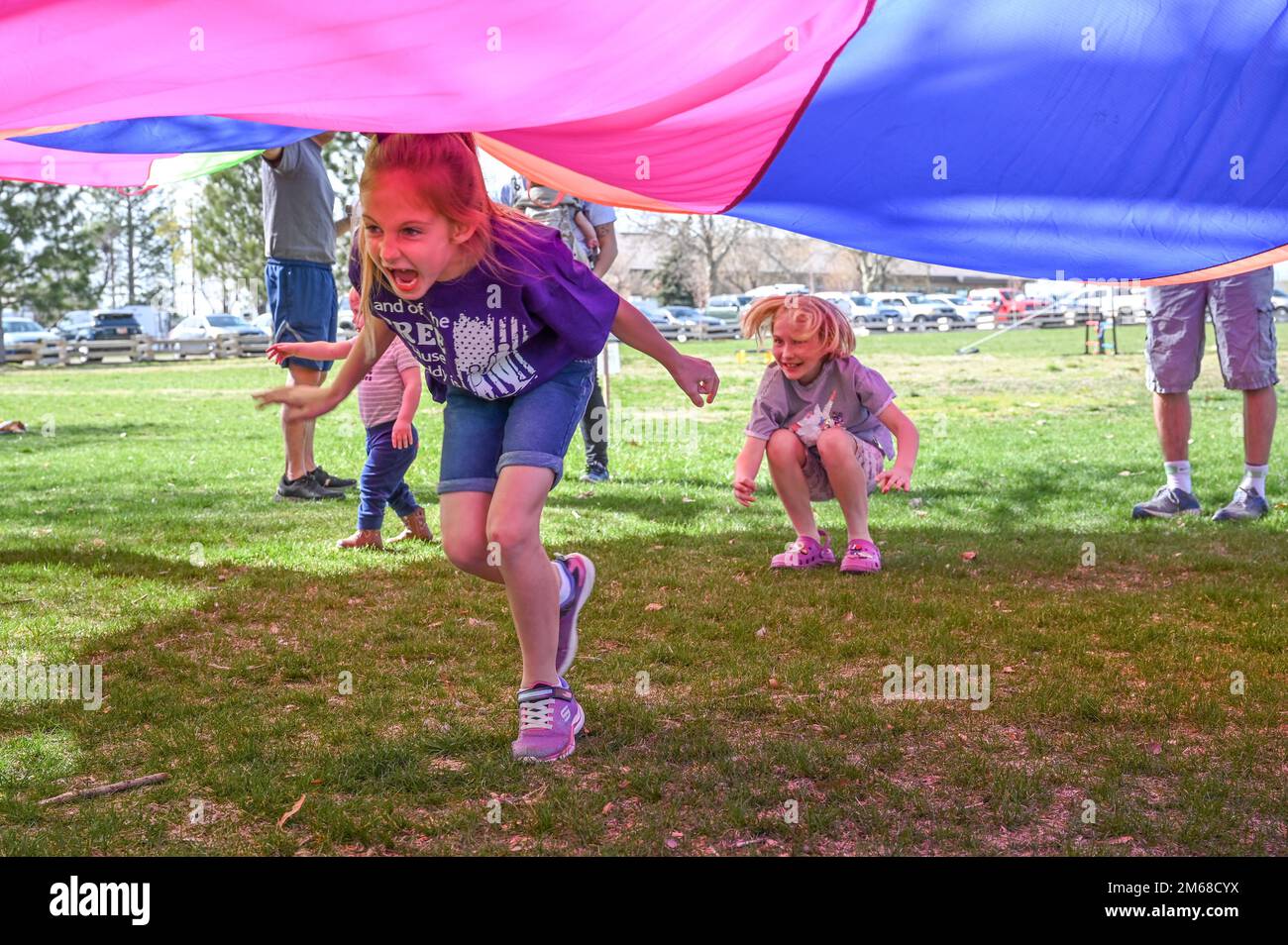 Children run under a parachute during the “Show Up for Military ...
