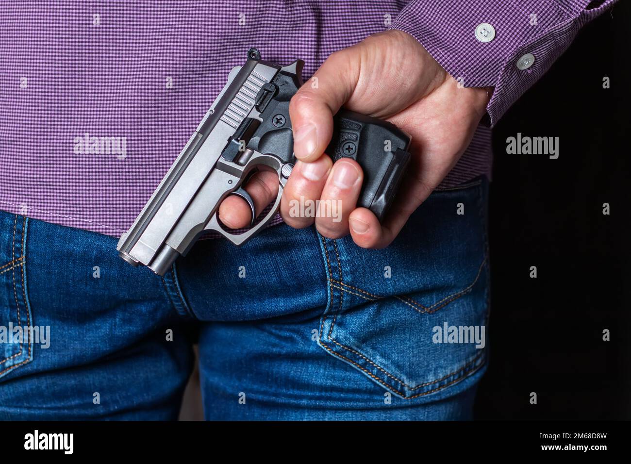 Man In a shirt with pistol on his back. Person holds firearm for attack ...