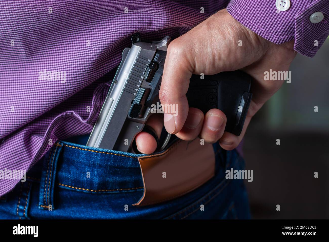 Man In a shirt with pistol on his back. Person holds firearm for attack ...