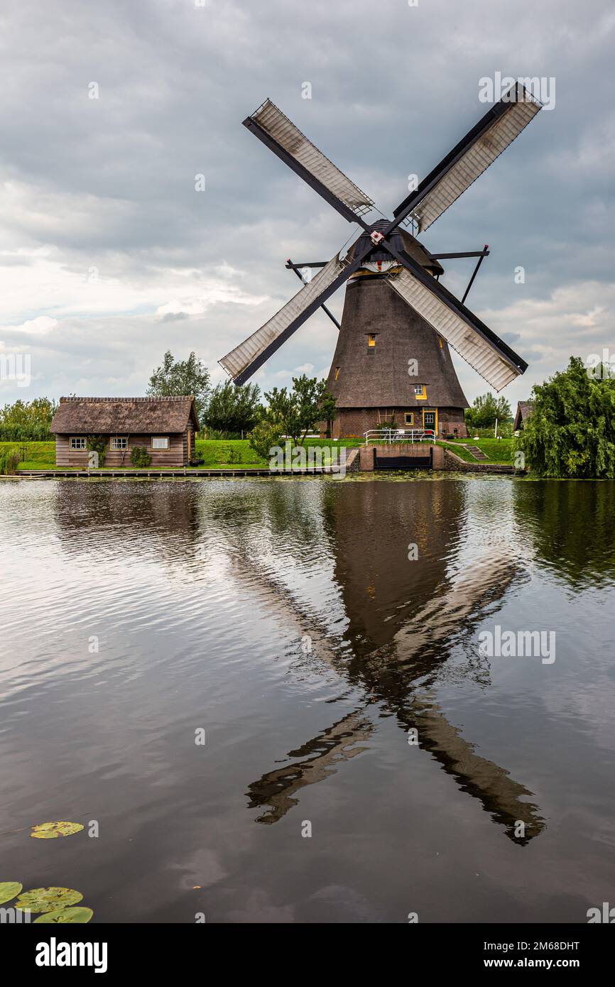wind pump windmill at a canal at kinderdijk with small house nearby ...