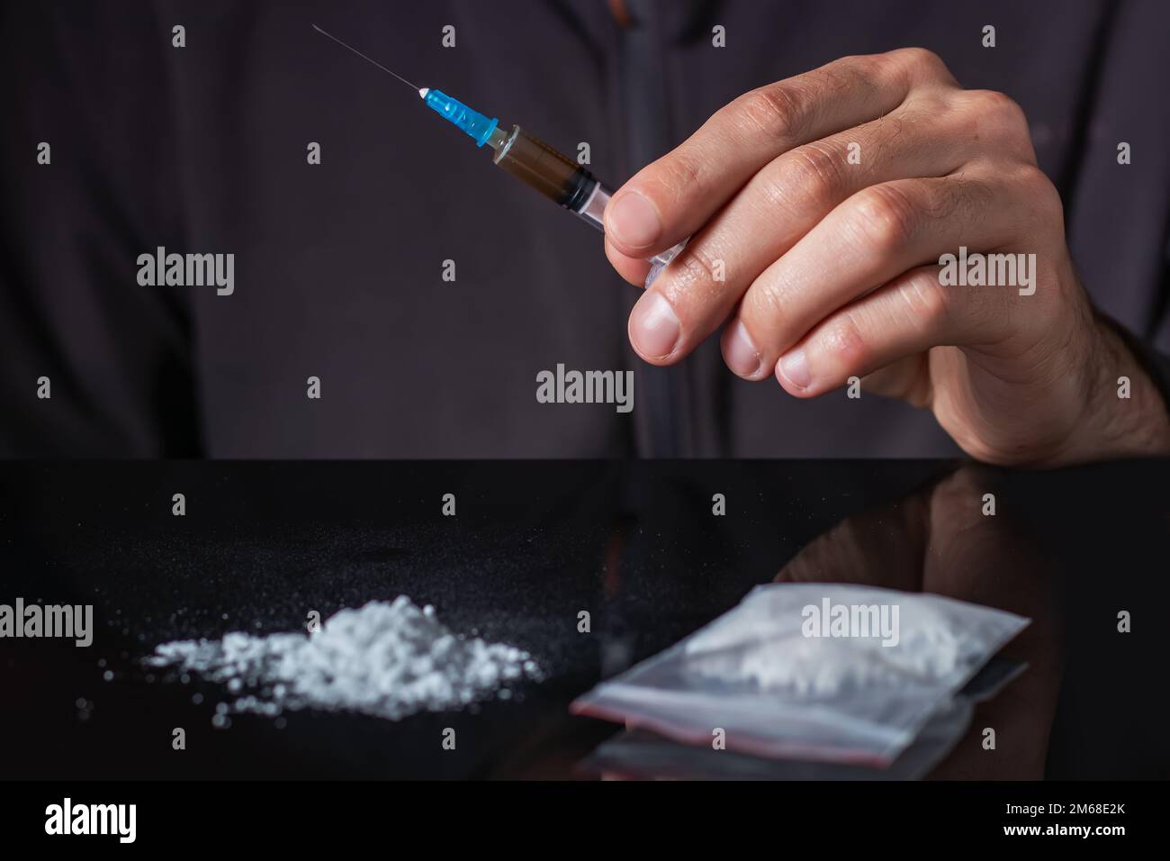 Drug syringe in hand. A drug addict with another dose of the drug in ...