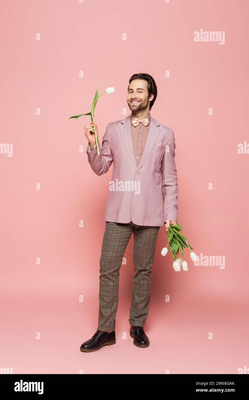 Stylish host of event holding bouquet of white tulips on pink ...