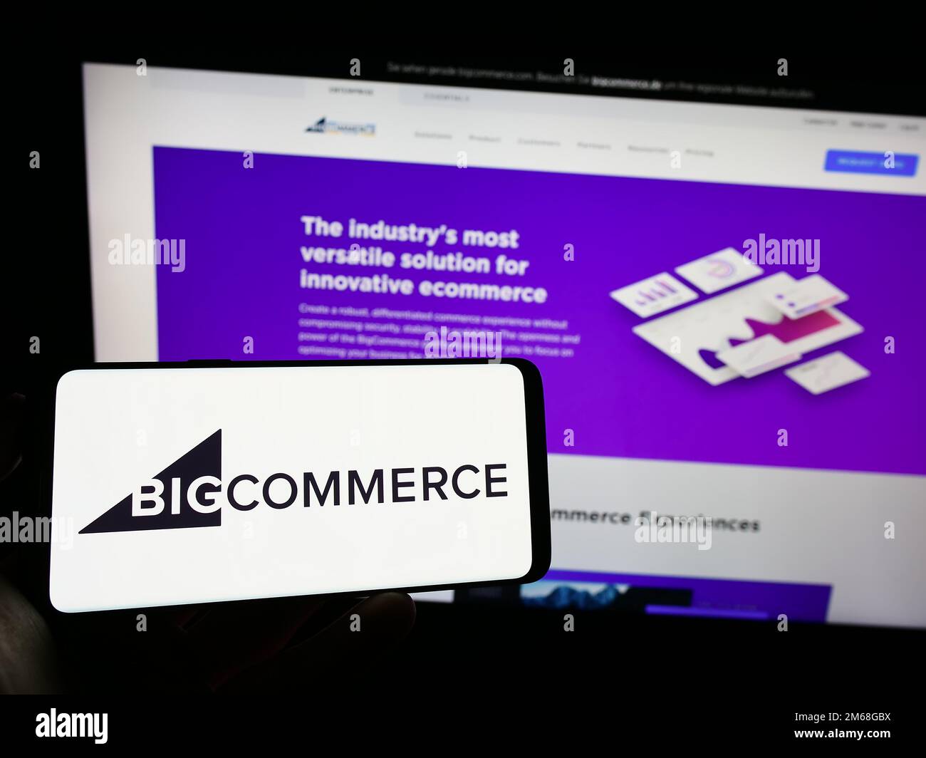Person holding cellphone with logo of US e-commerce company BigCommerce Inc. on screen in front ...