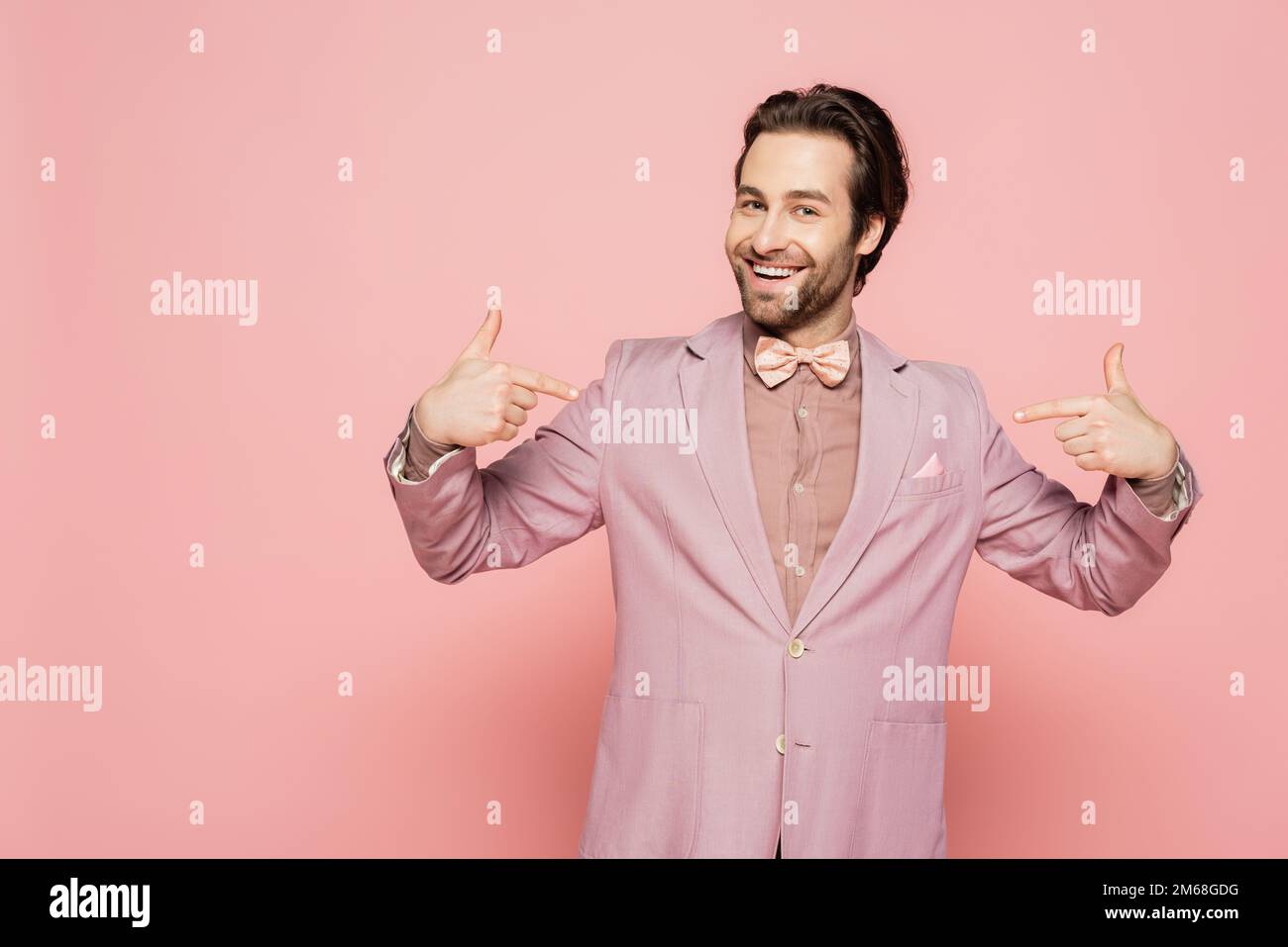 Positive host of event in jacket pointing with fingers on pink ...