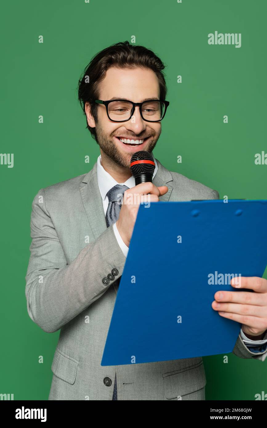 happy news anchor in suit and eyeglasses talking in microphone while ...