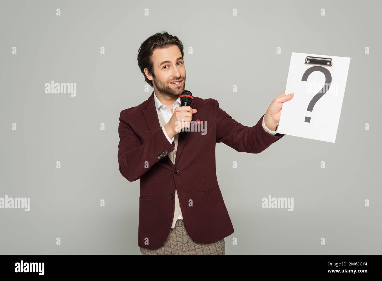 bearded host of event in formal wear talking in microphone while ...