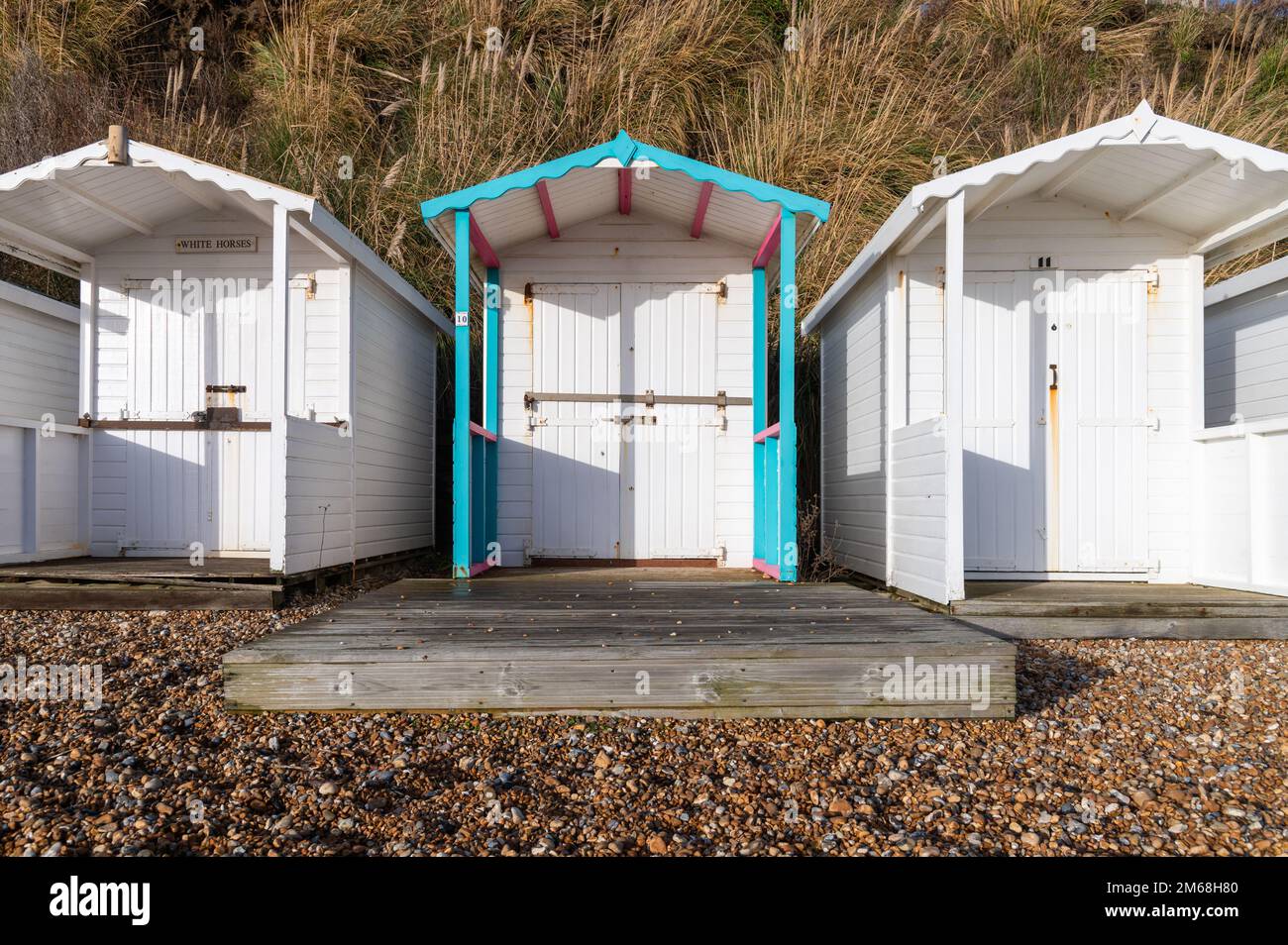 Three white wooden beach huts at Bexhill-on-Sea on a sunny day Stock ...