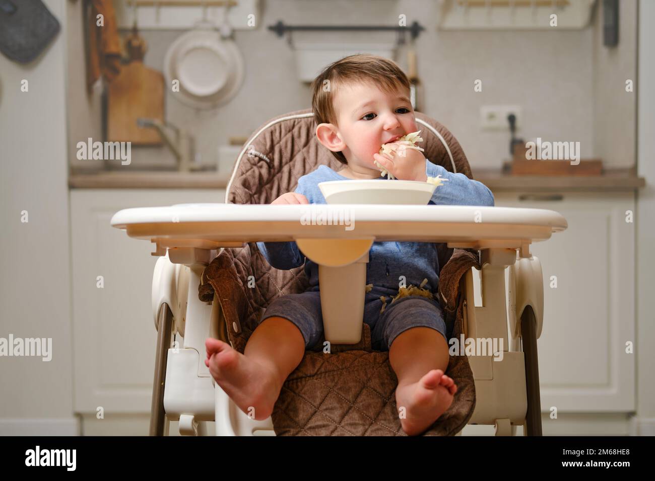 A funny child is eating a grated apple with his mouth full while ...