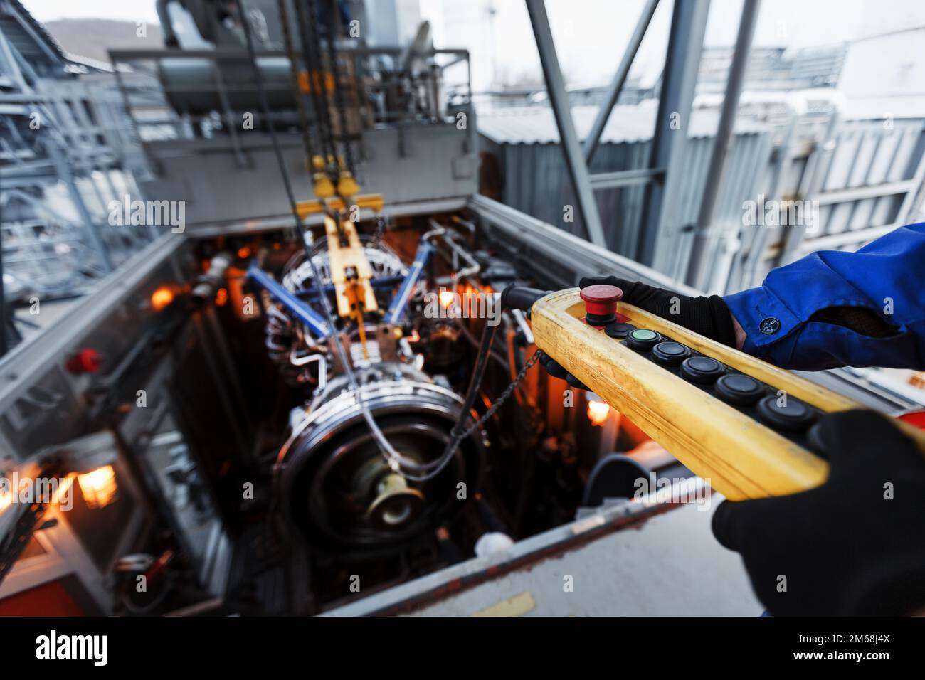 The engine of a gas turbine compressor hangs on a crane during ...