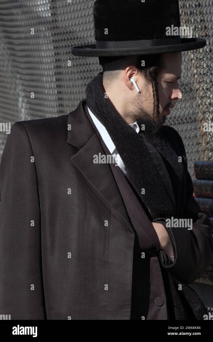 A hasidic jewish man mixes tradition with technology wearing both peyus ...