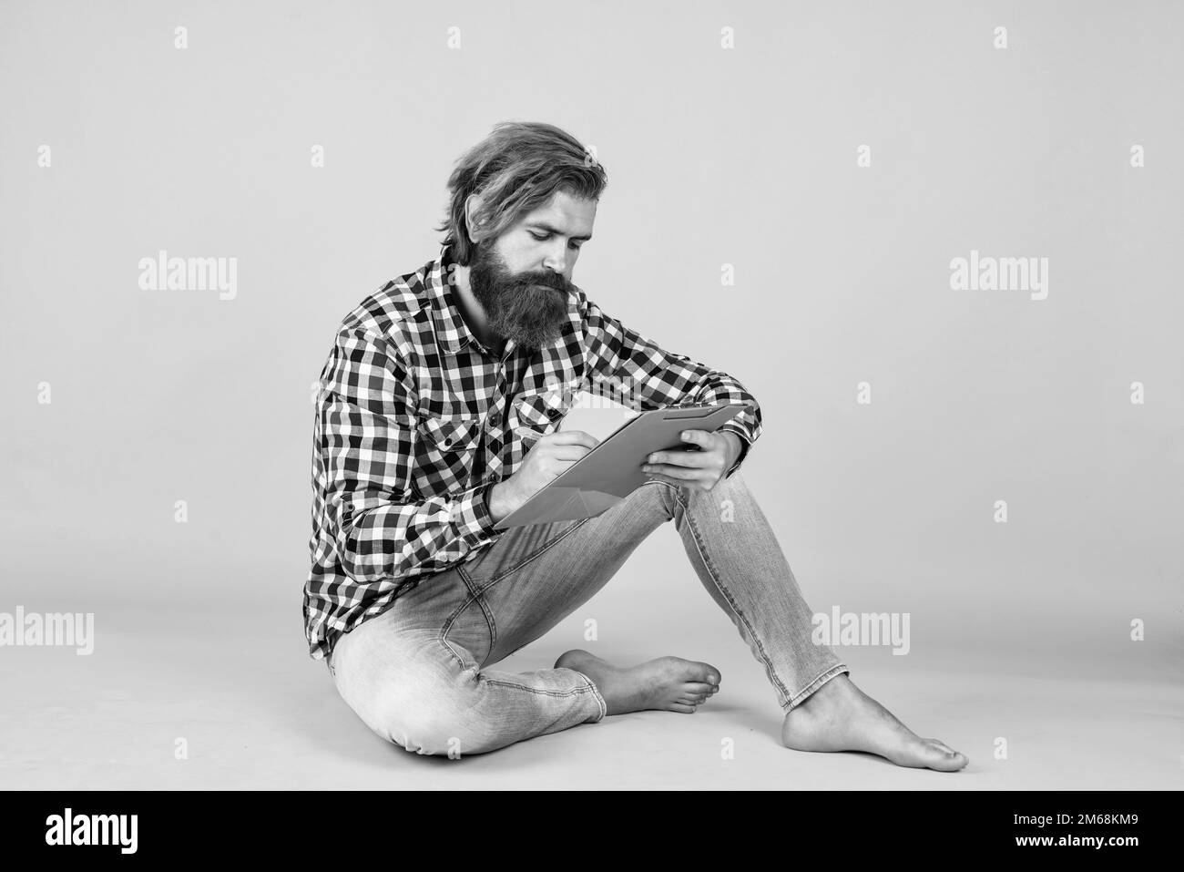 bearded student making notes in his paper. casual styled man writing in ...