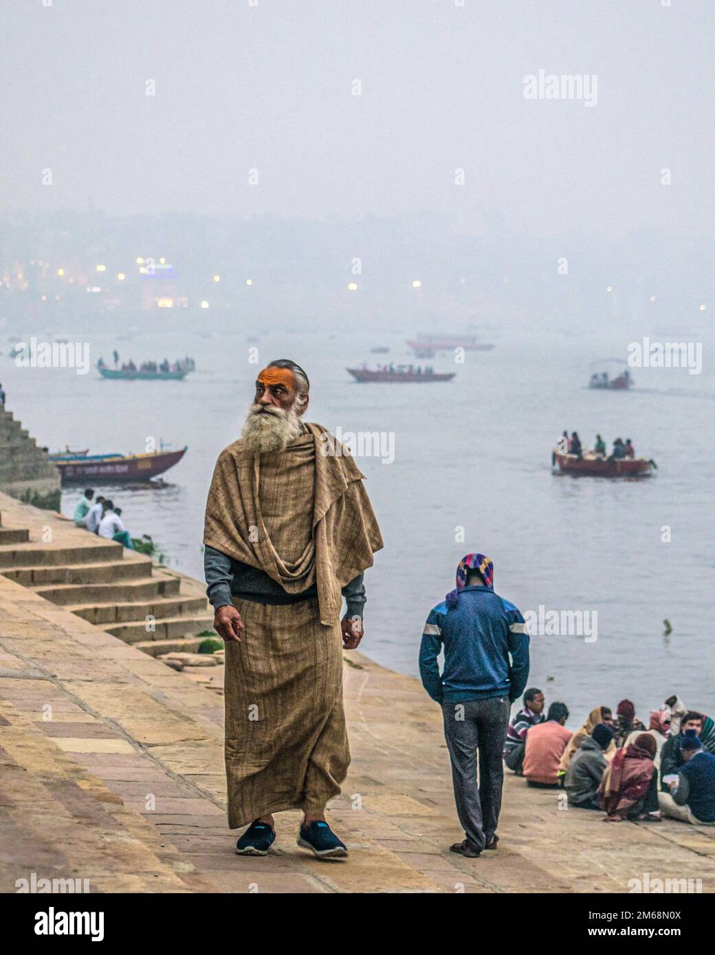 A vertical shot of a sadhu walking on the Ghats in Varanasi riverfront ...