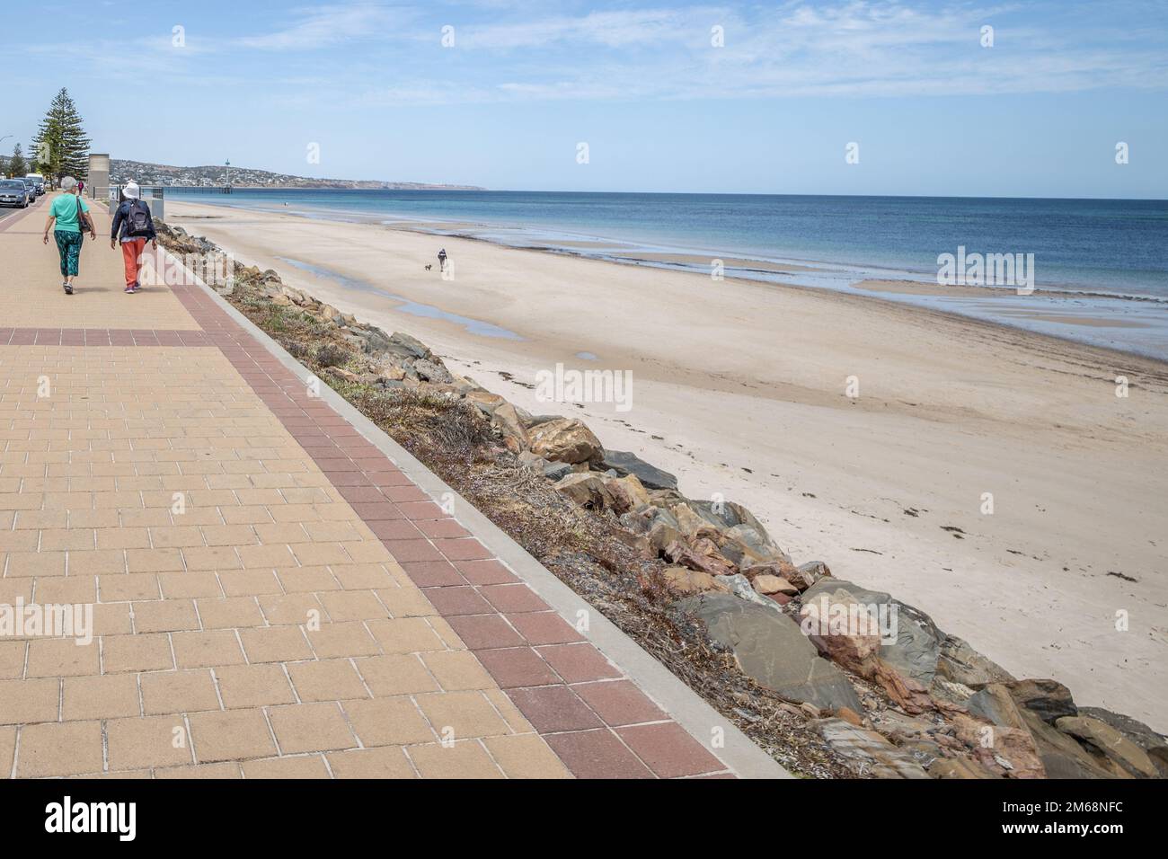 Two women walking along the pavement beside the seaside on a summers ...