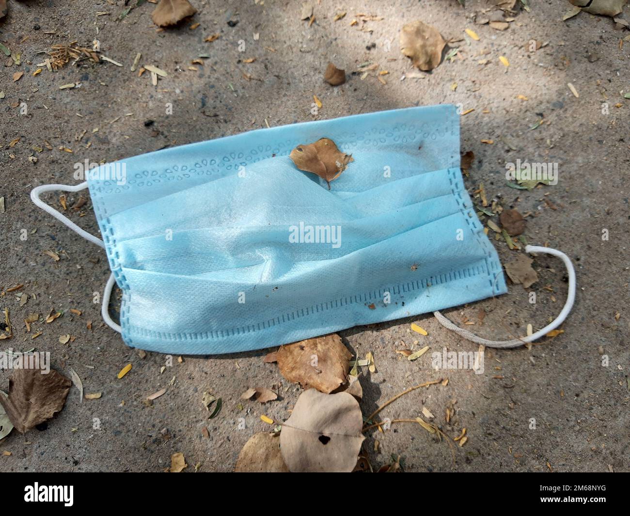 Used disposable medical Blue face mask discarded on the ground of a ...
