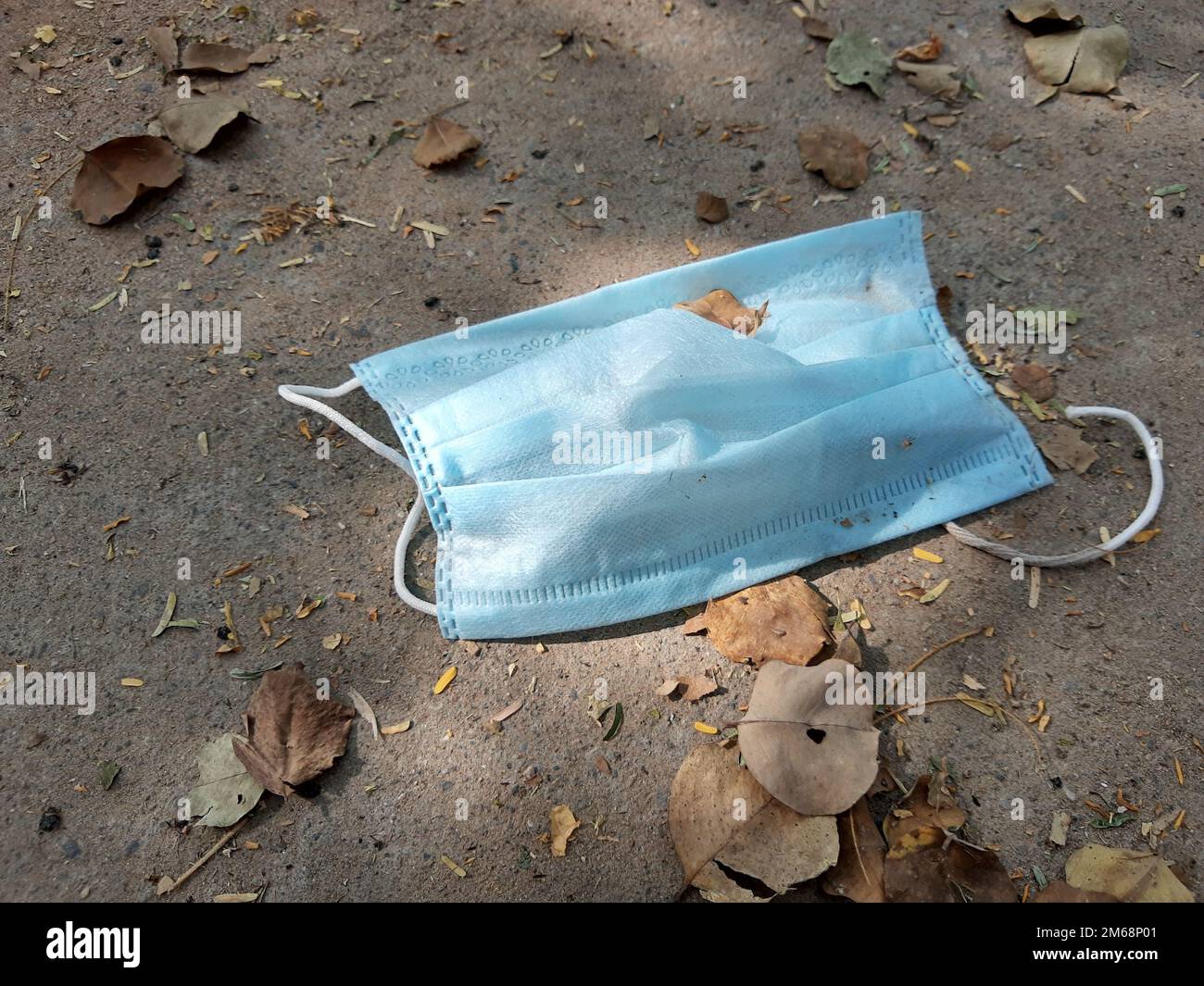 Used disposable medical Blue face mask discarded on the ground of a ...