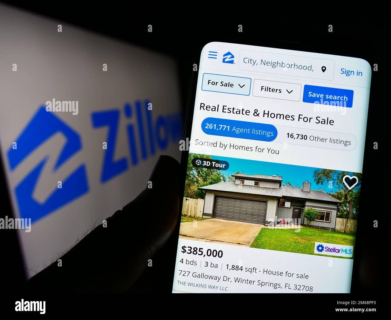 Person holding smartphone with webpage of US real estate marketplace ...