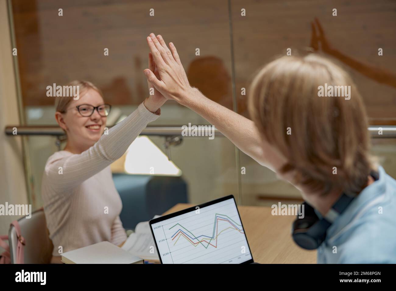 Two happy friends students clap hands after finishing work on project ...