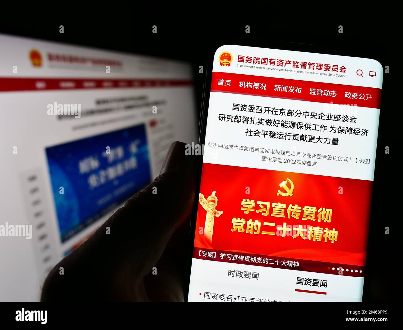 Person holding cellphone with webpage and logo of Chinese state-owned ...