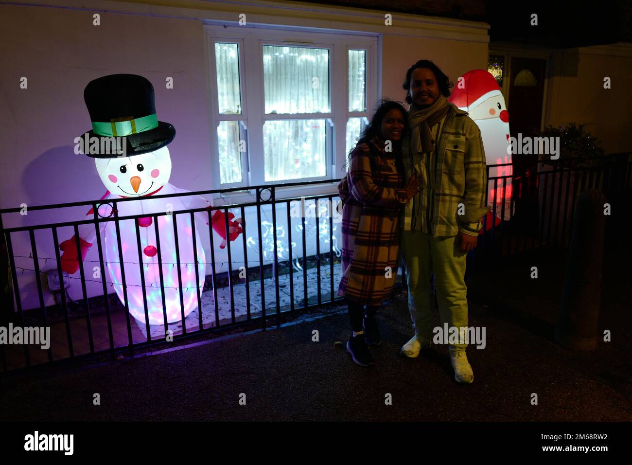 couple photographed next to a snowman at night Stock Photo - Alamy