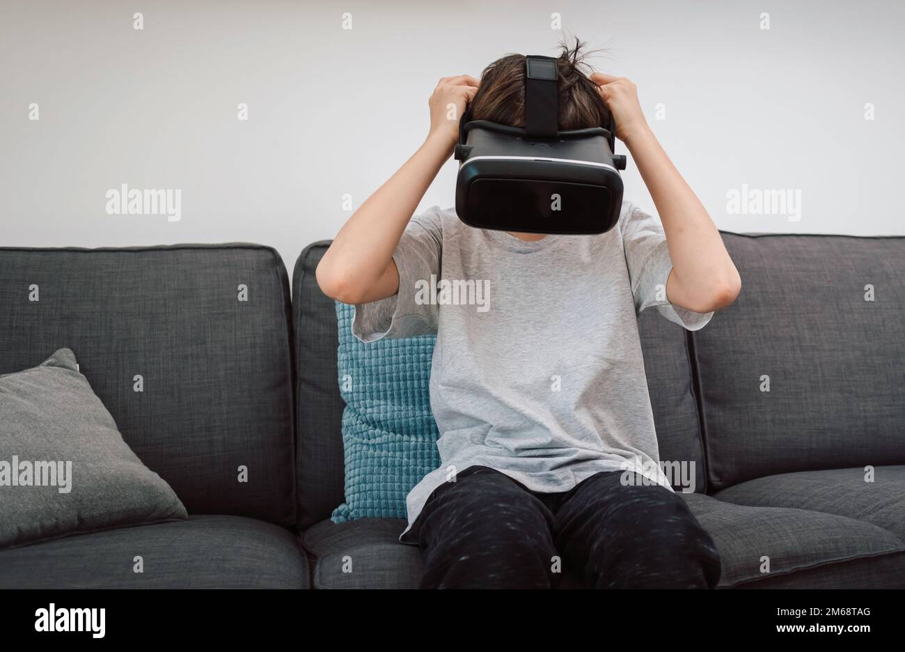 Caucasian male child putting on a virtual reality headset, looking ...
