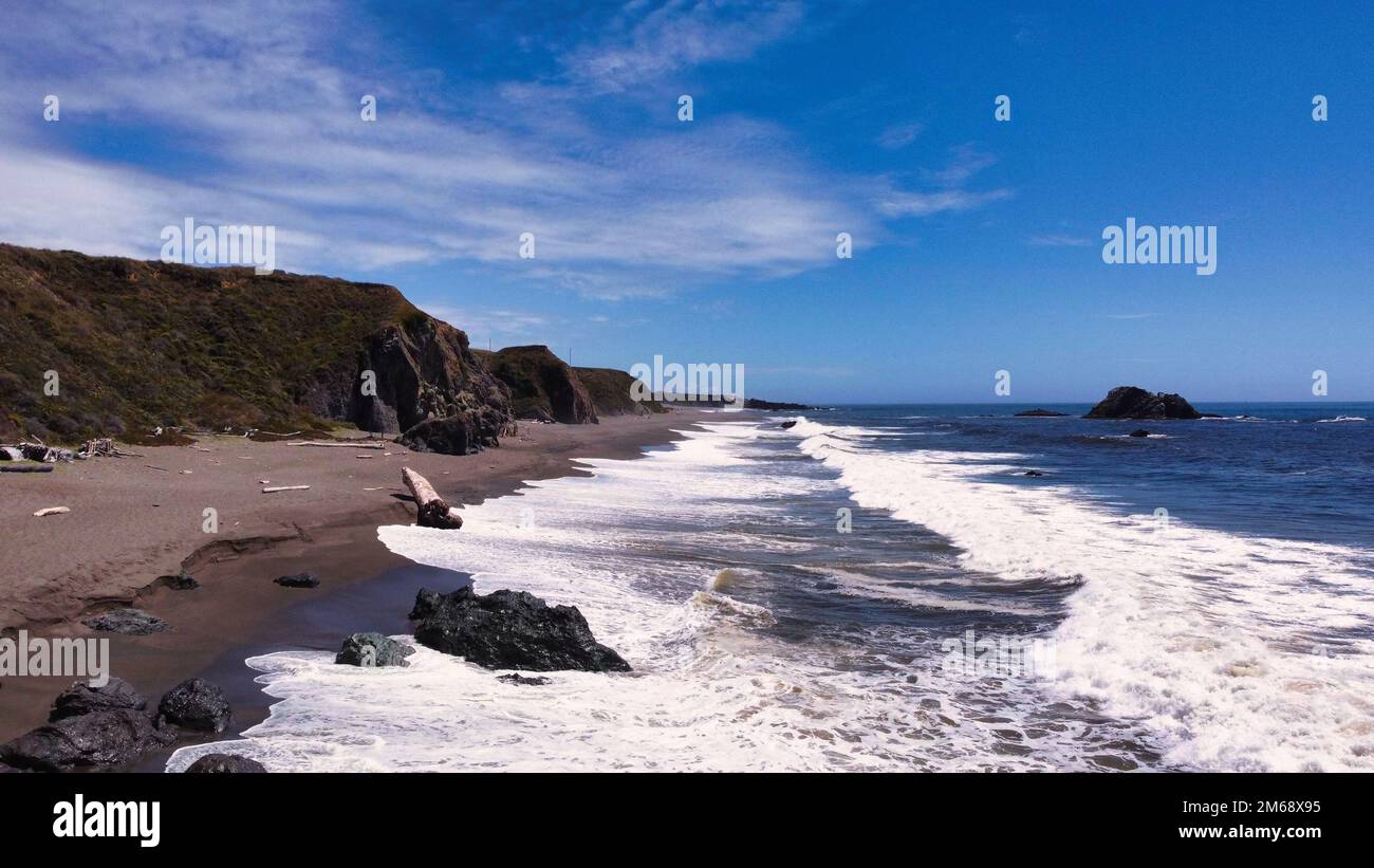 An aerial shot of foamy waves crashing the Goat Rock beach of Jenner in ...