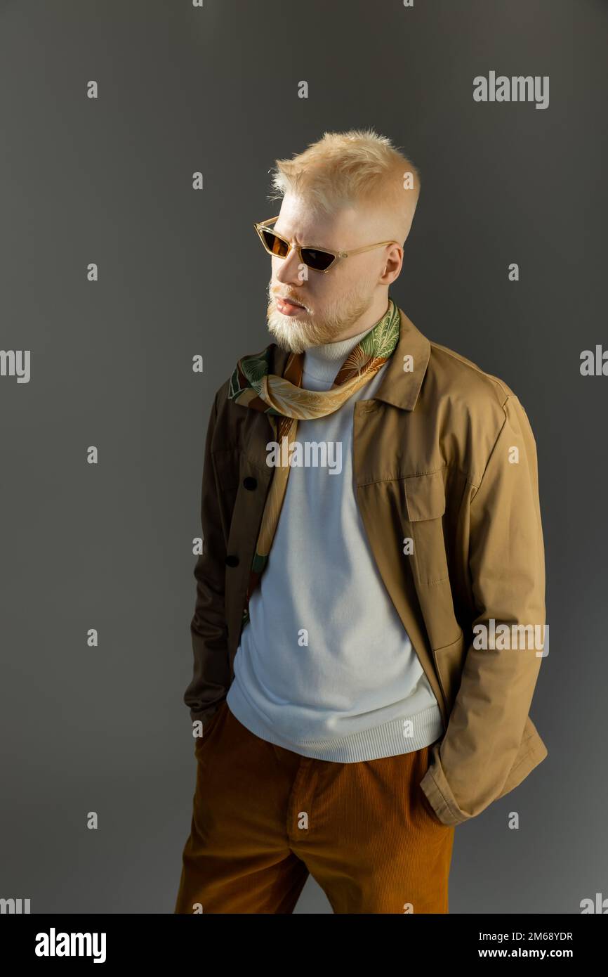 sunlight on face of stylish albino model in sunglasses posing with ...