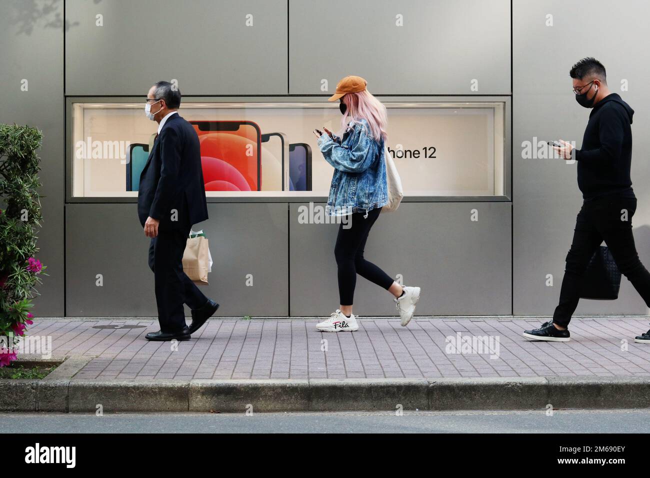 TOKYO, JAPAN - April 8, 2021: Pedestrian using smartphones pass an ...